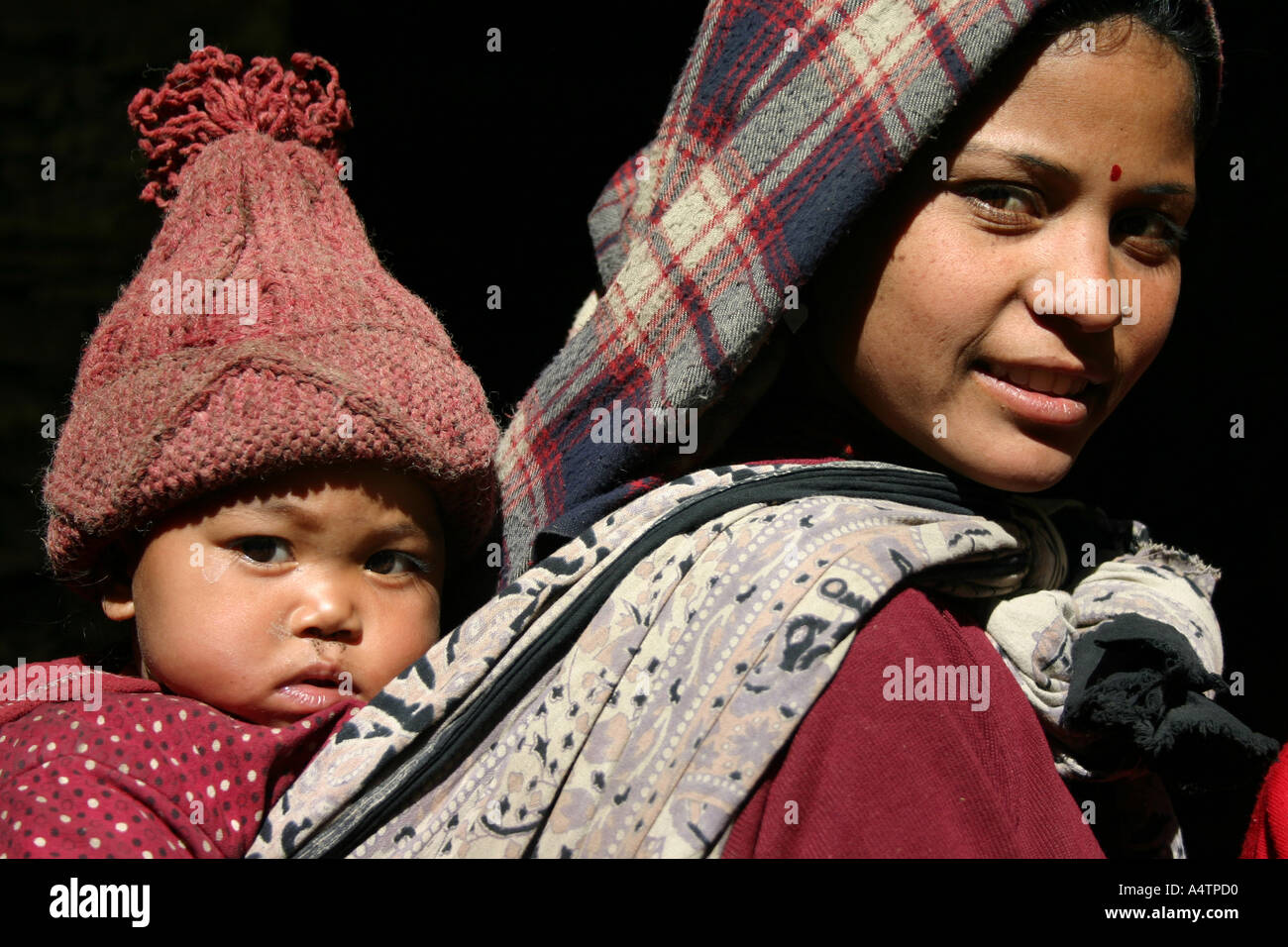 A young Nepalese mother carries her child on her back in the Upper ...