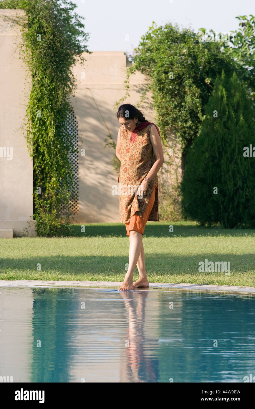 Woman dipping toes into swimming pool Stock Photo - Alamy