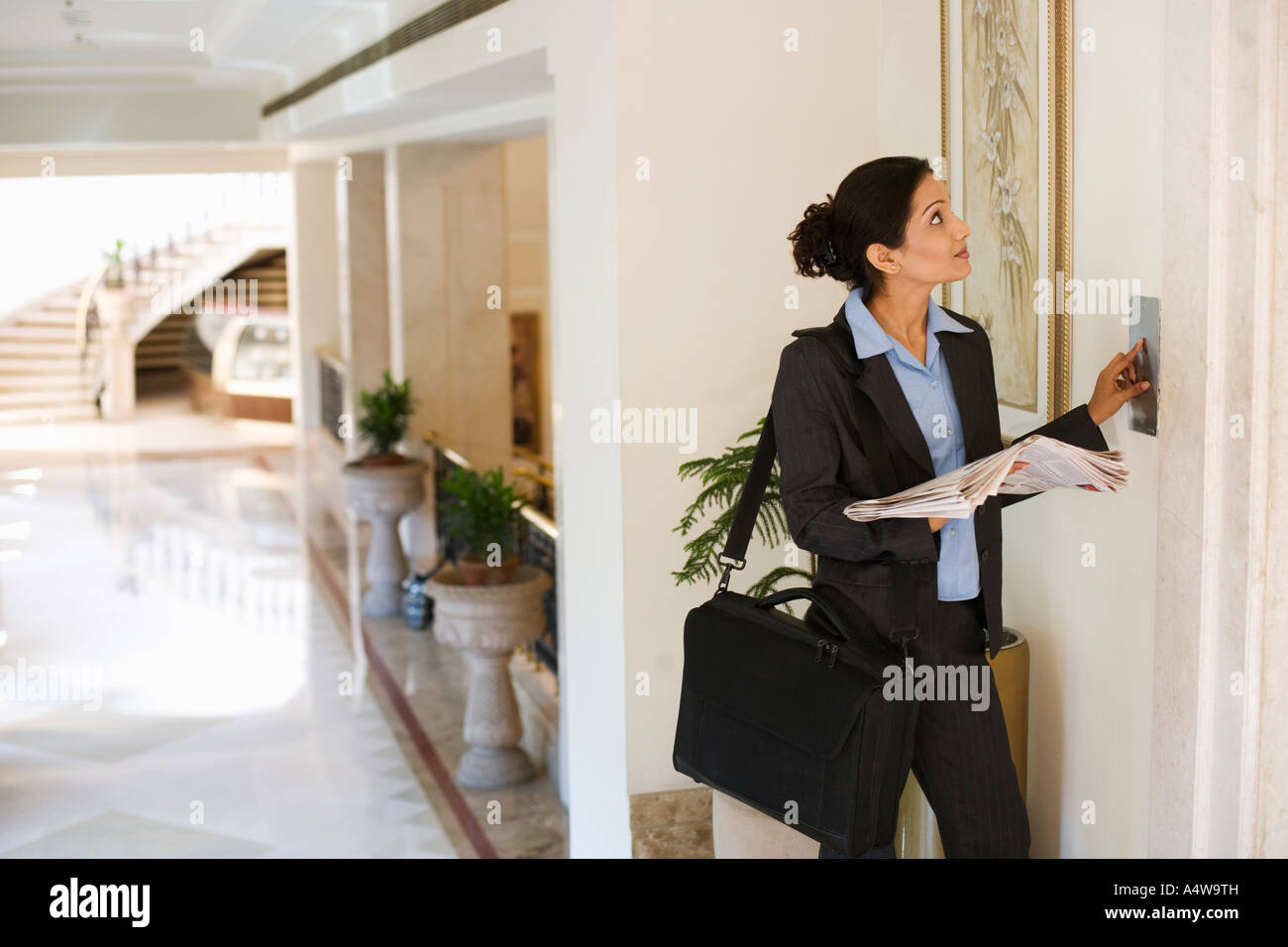 Businesswoman reading newspaper while waiting for elevator Stock Photo ...
