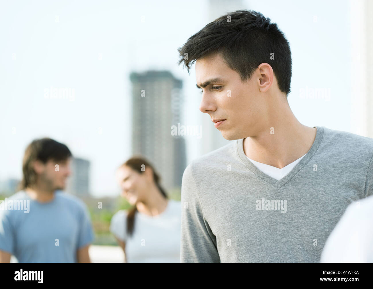 Young man looking to the side, young couple in background Stock Photo ...