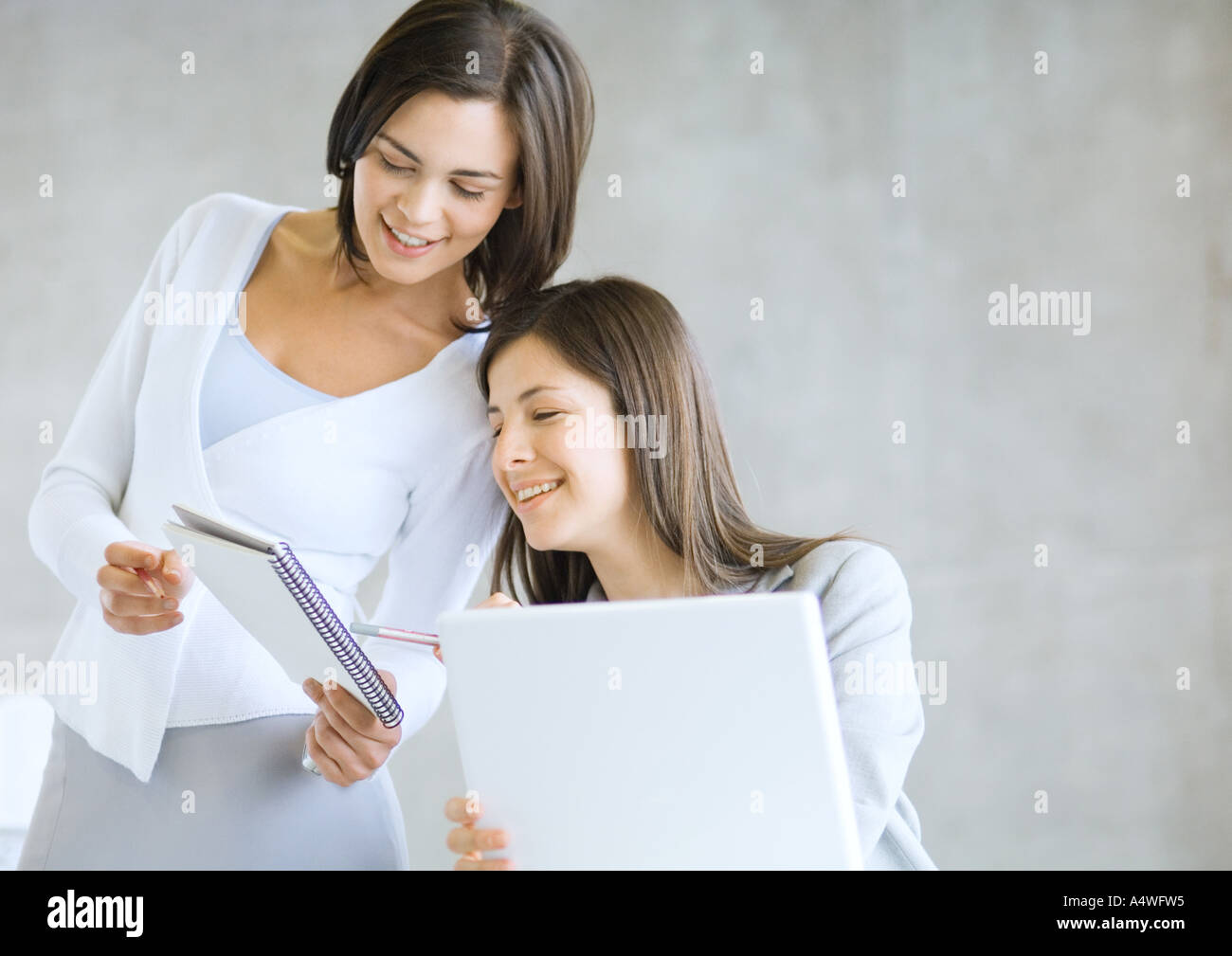 Woman showing colleague notebook Stock Photo - Alamy