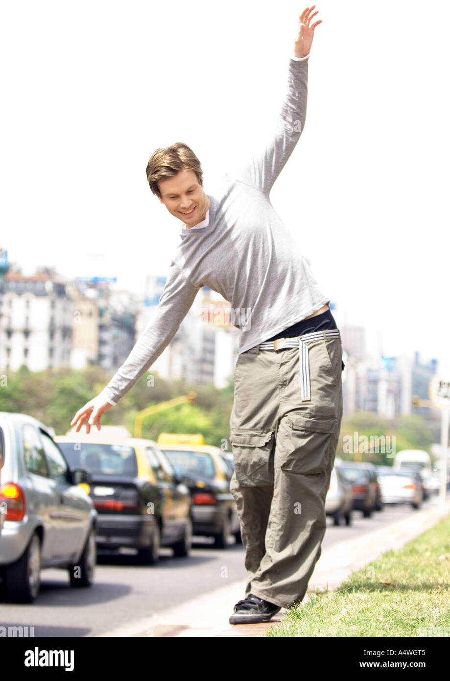 Young man catching balance as he walks on curb Stock Photo - Alamy