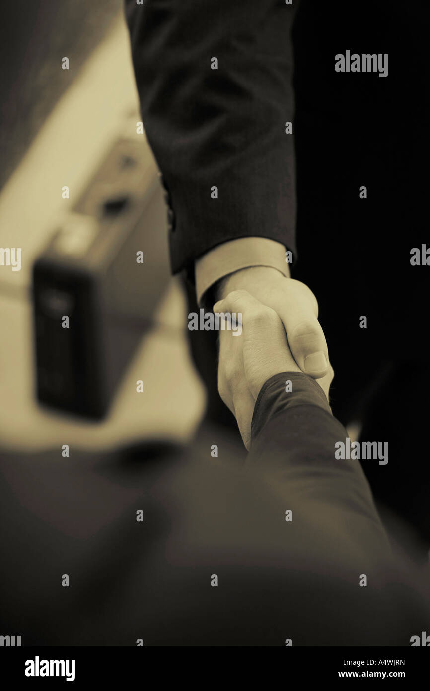 Two businessmen give a handshake with a briefcase in the background and ...