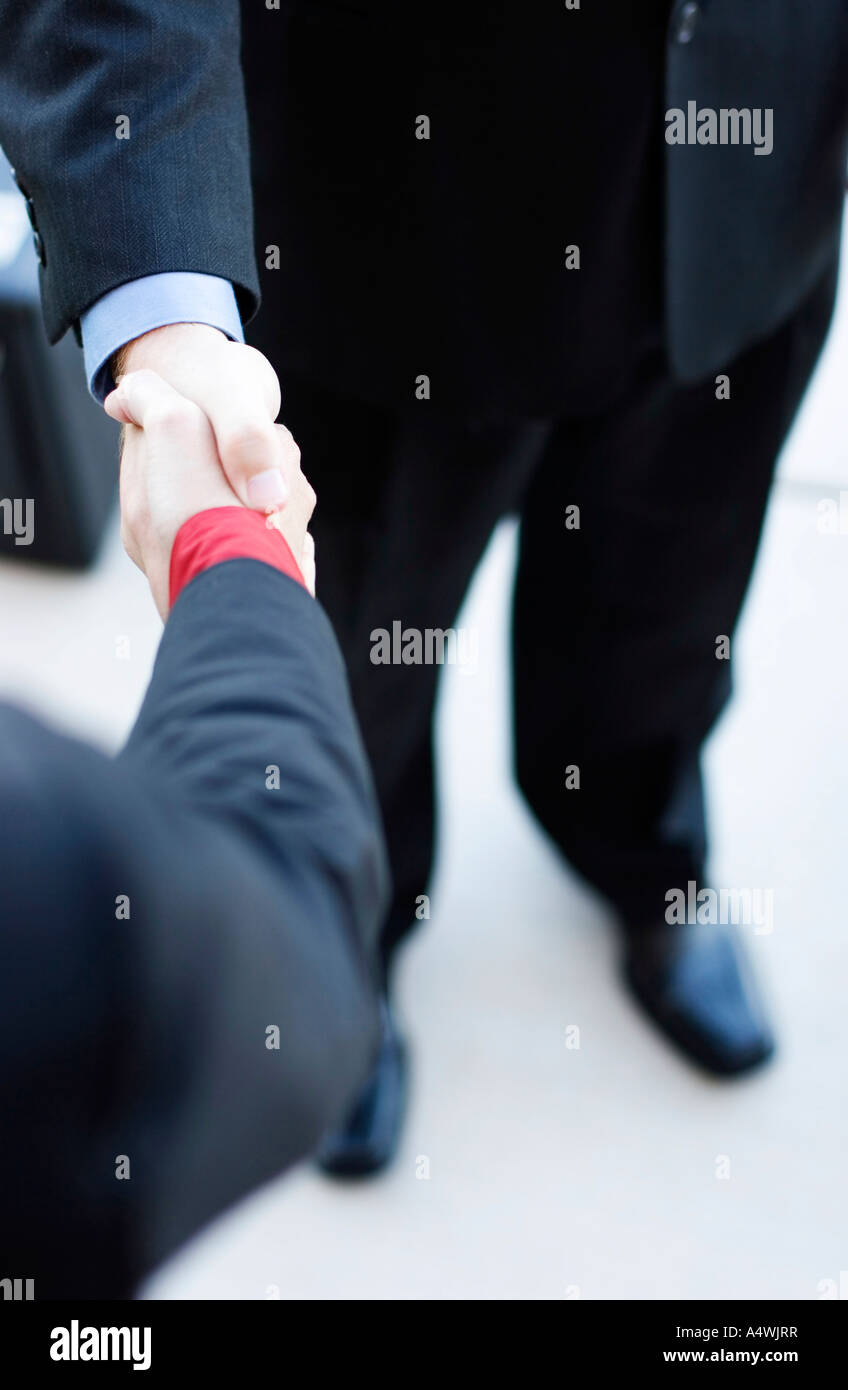 Two businessmen give a handshake with briefcase in the background Stock ...