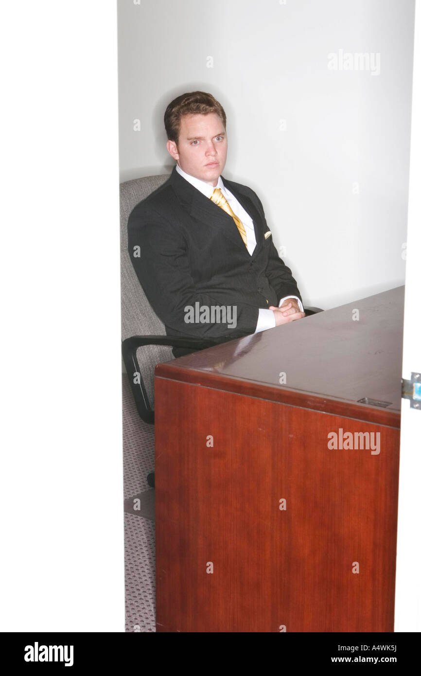 Businessman sitting in his office looking out of the door with despair ...