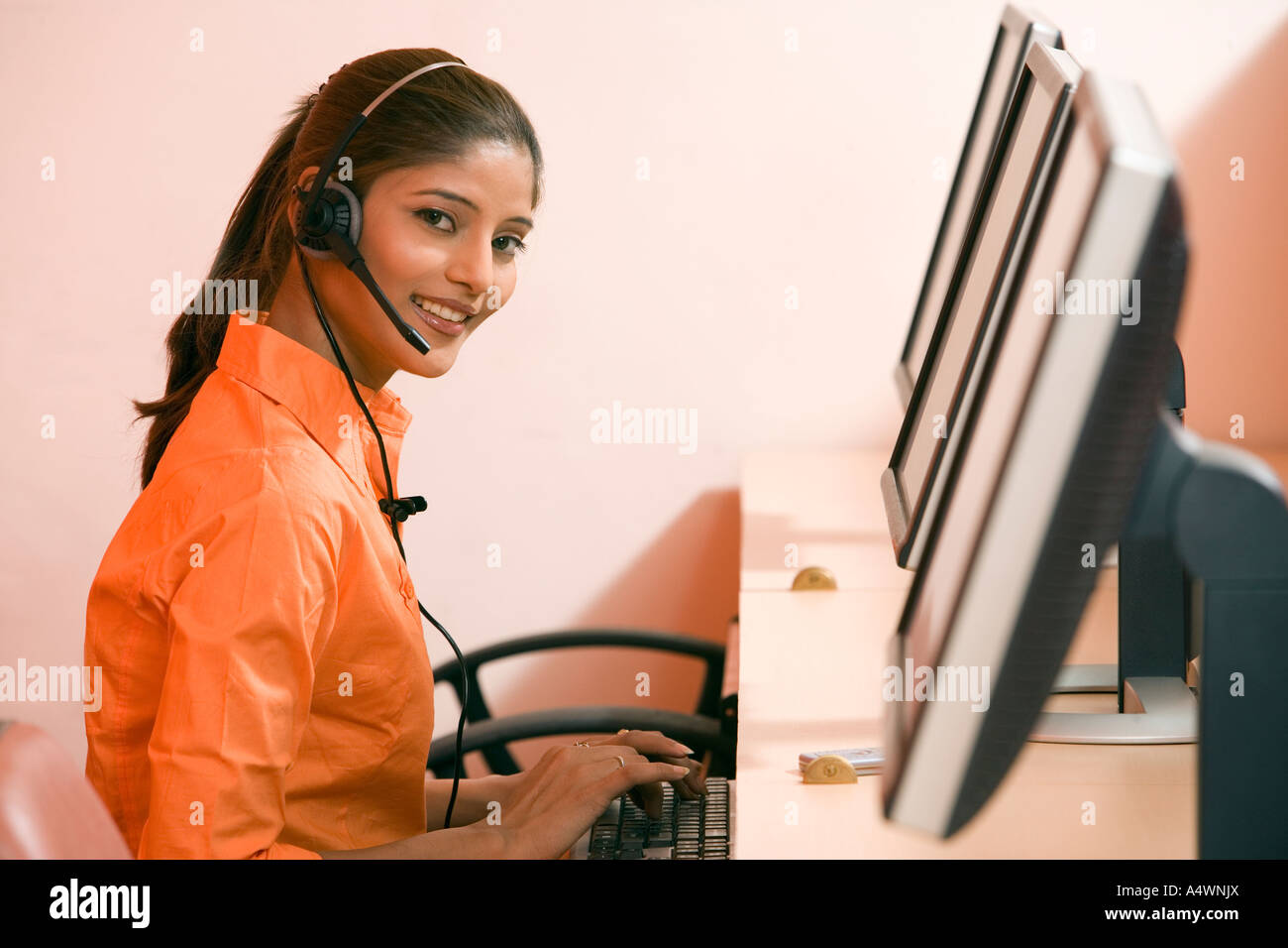 Businesswoman wearing headset while working at computer Stock Photo - Alamy