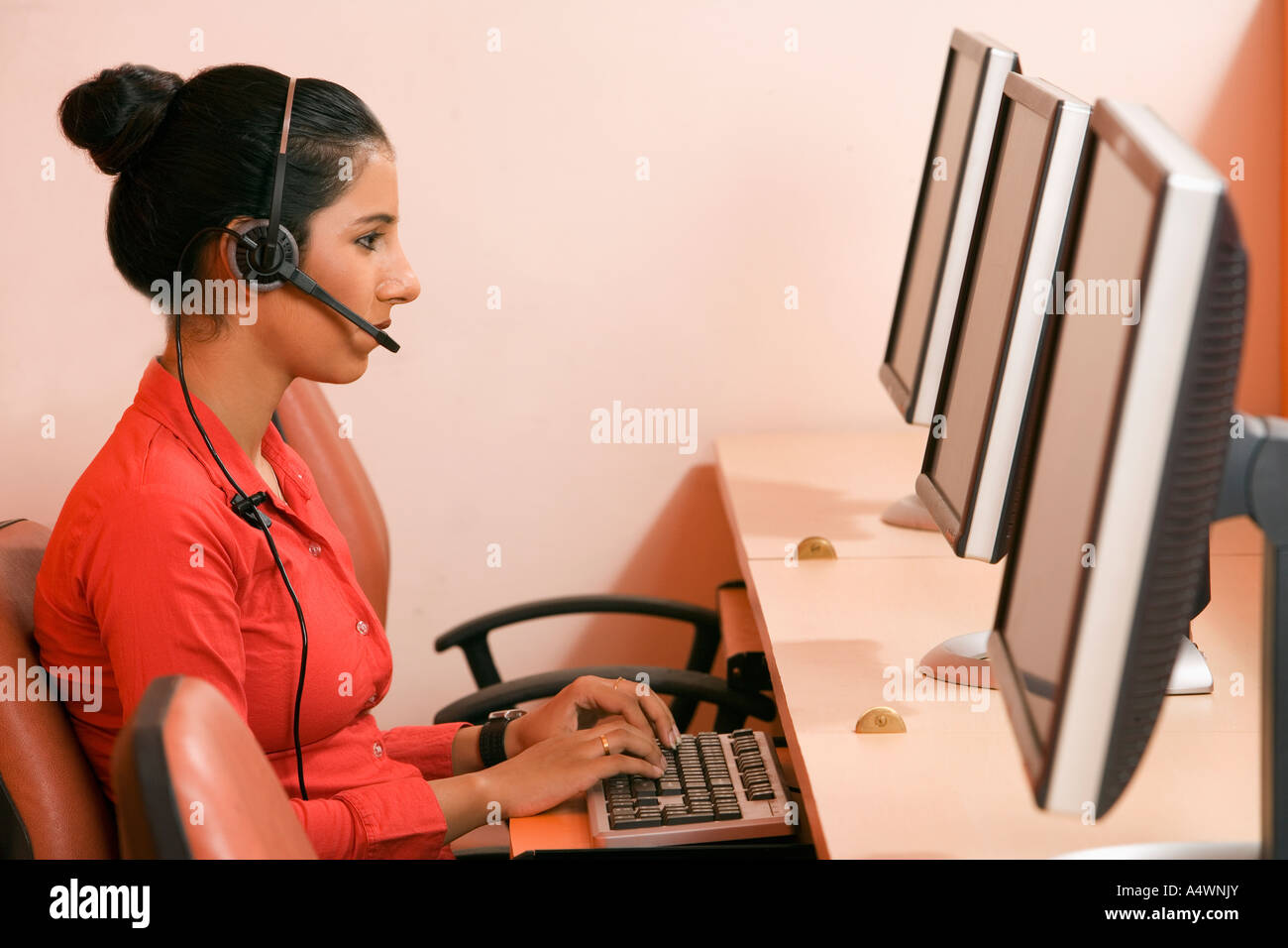 Businesswoman wearing headset while working at computer Stock Photo - Alamy