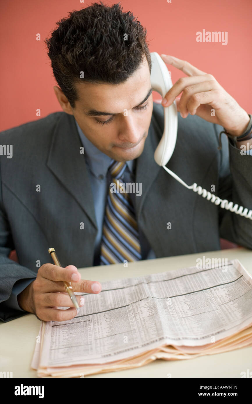 Businessman reading newspaper while on the phone Stock Photo - Alamy