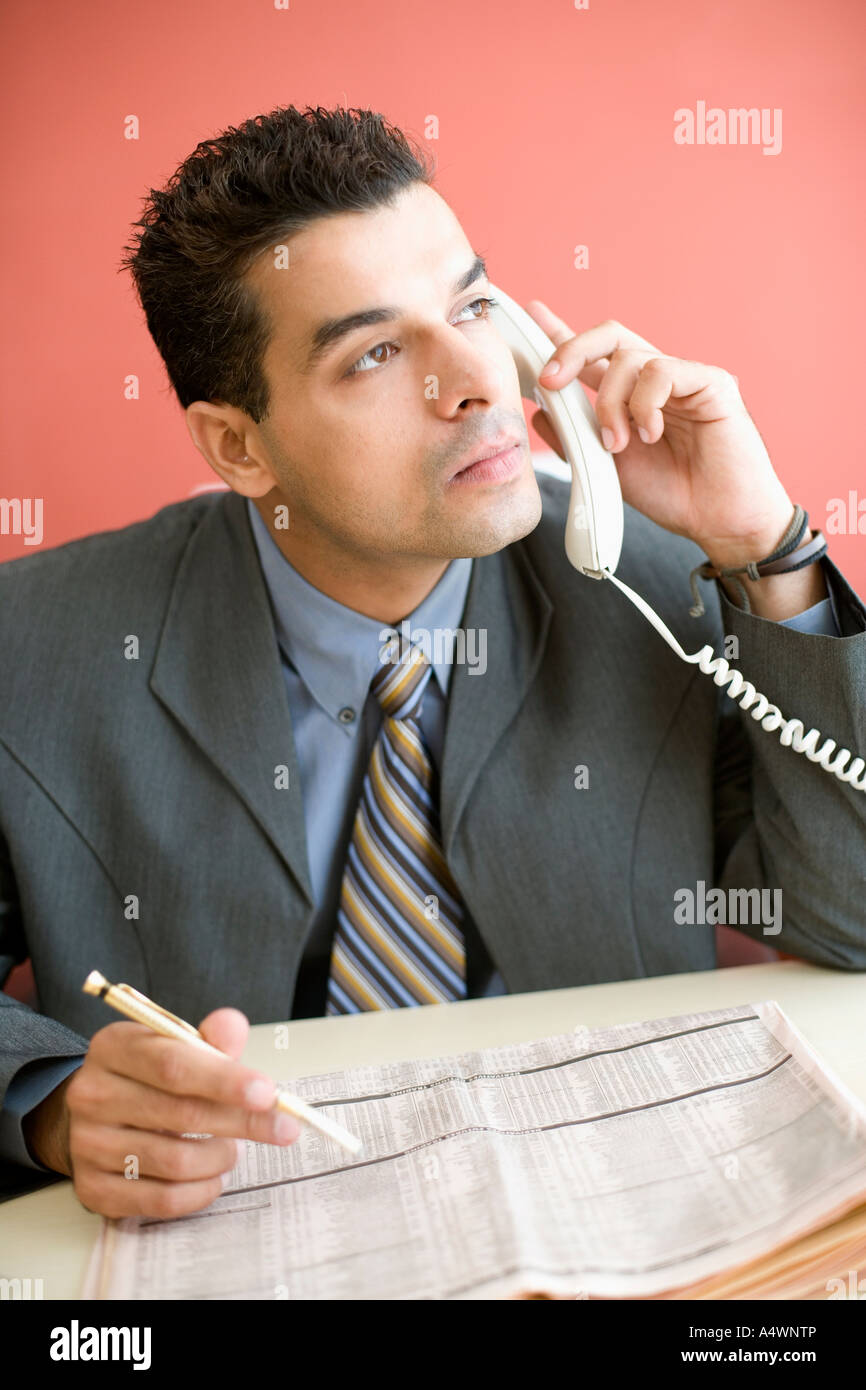 Businessman reading newspaper while on the phone Stock Photo - Alamy