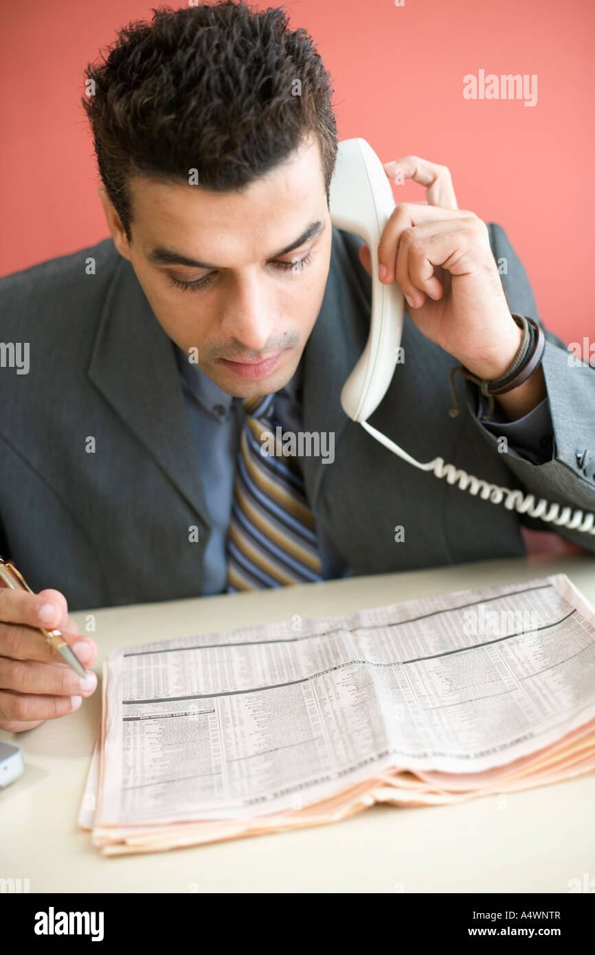 Businessman reading newspaper while on the phone Stock Photo - Alamy