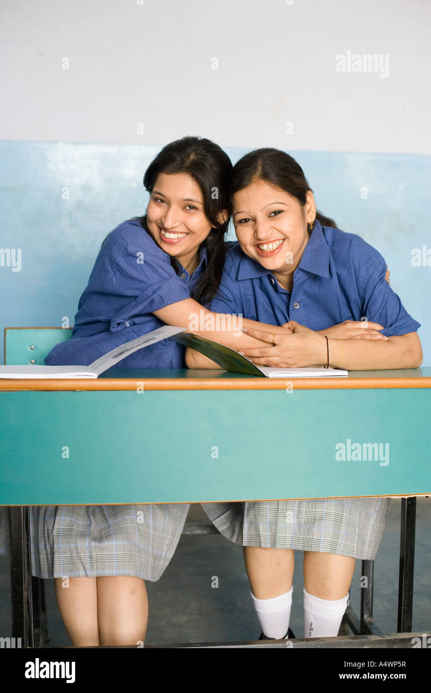 Female students hugging at shared desk Stock Photo - Alamy