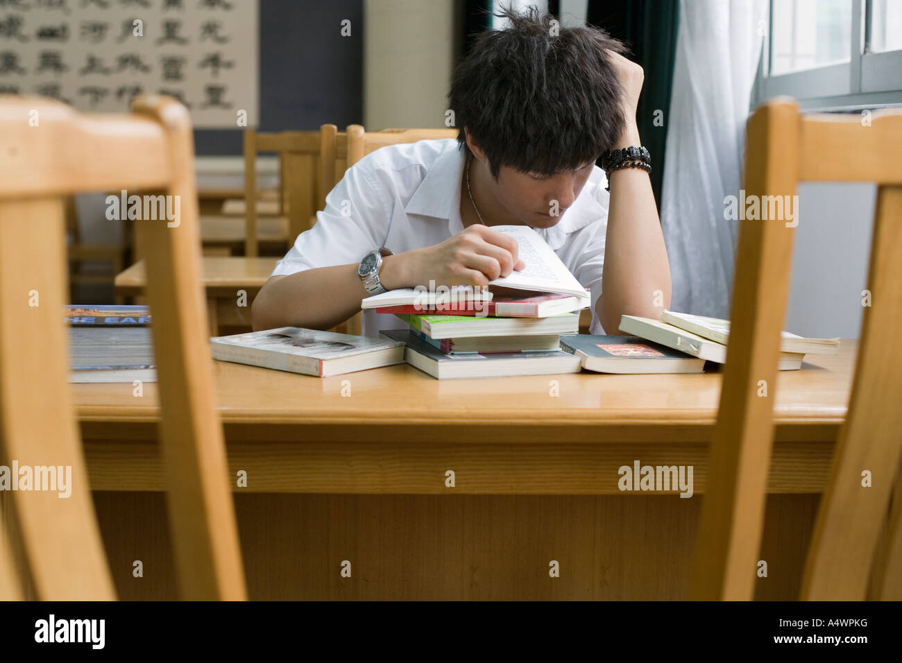 Young man reading at a table Stock Photo - Alamy