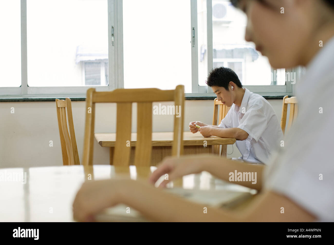 Male student listening to an mp3 player while reading Stock Photo - Alamy