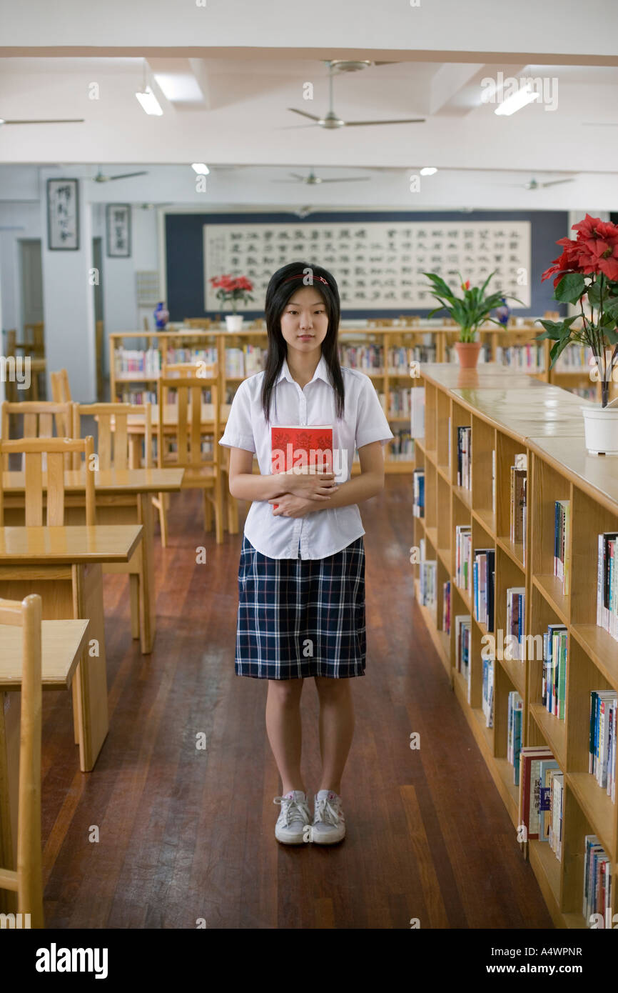 Female student holding a book in library Stock Photo - Alamy