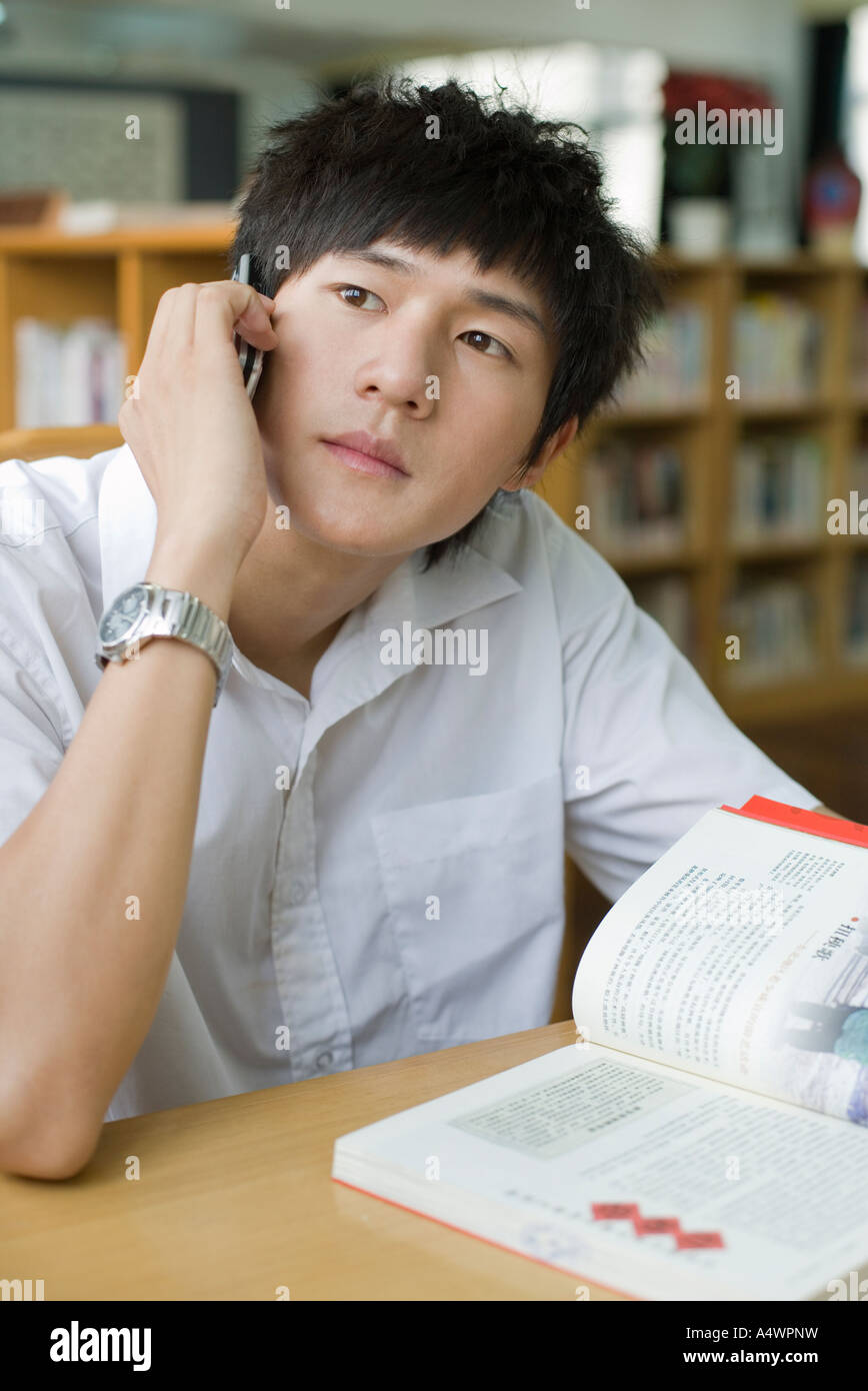 Male student talking on his cell phone while reading Stock Photo - Alamy