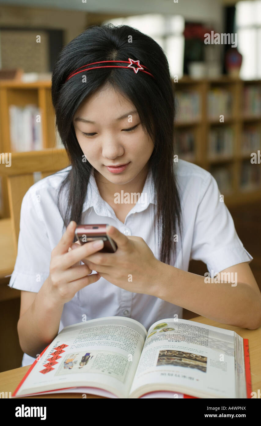 Female student using her cell phone while reading Stock Photo - Alamy