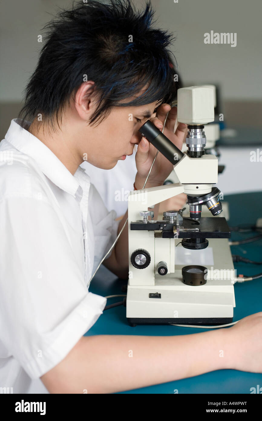 Male student using a microscope Stock Photo - Alamy