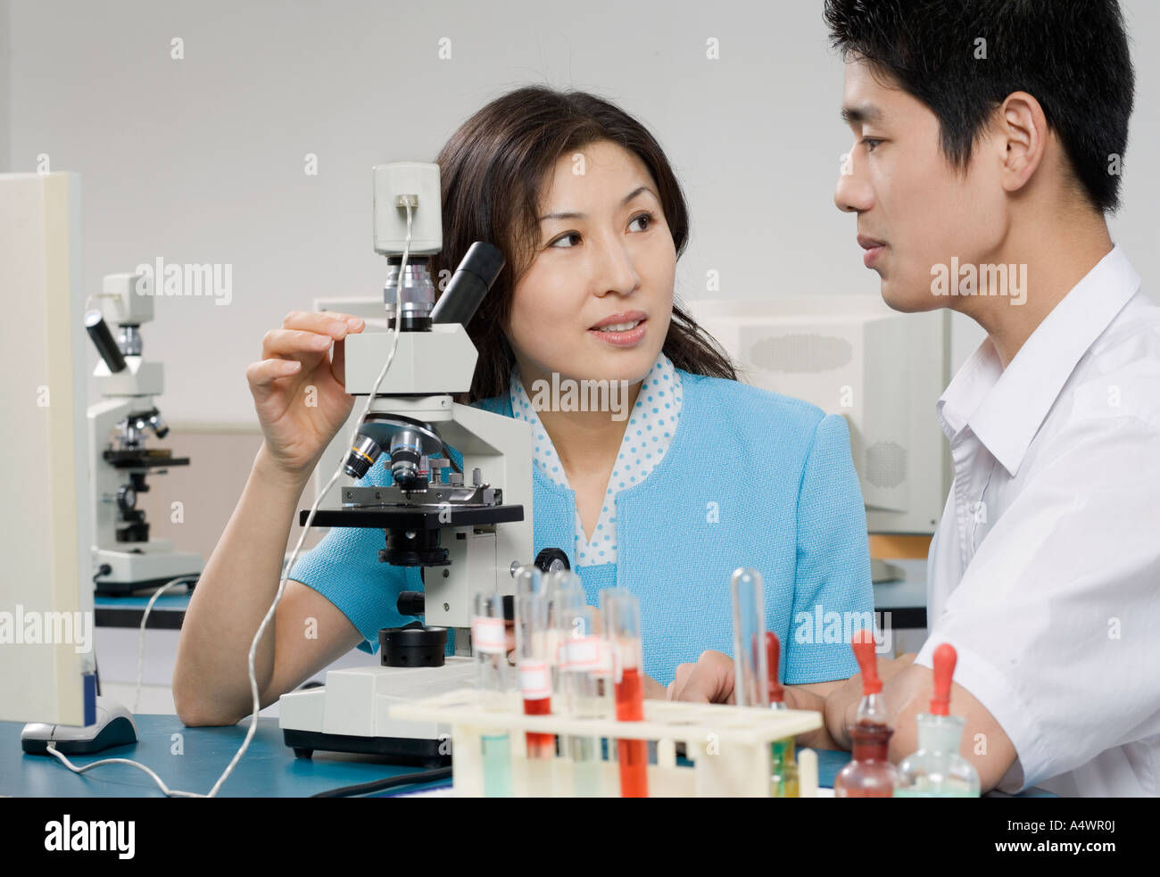 Teacher showing male student how to use a microscope Stock Photo - Alamy