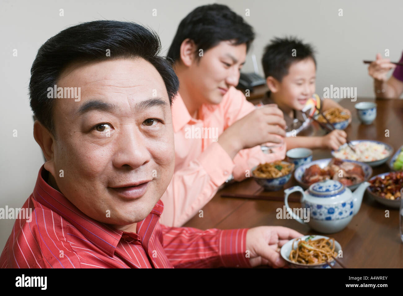 Middle-aged man sitting at dinner table with family Stock Photo - Alamy
