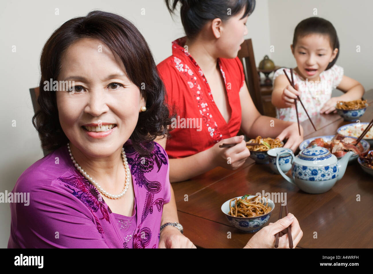 Middle-aged woman sitting at dinner table with family Stock Photo - Alamy