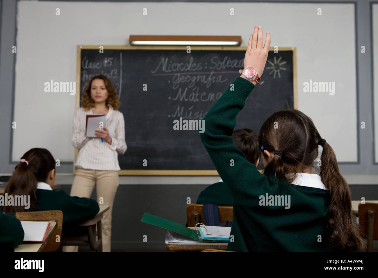 Young student raising her hand in class Stock Photo - Alamy