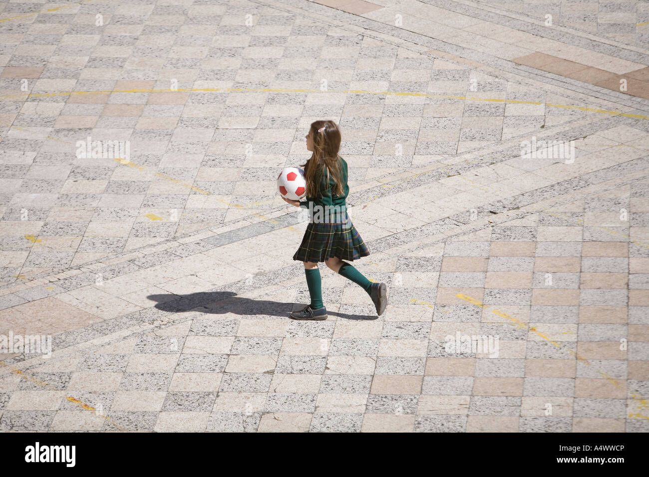 Young girl carrying a soccer ball in courtyard Stock Photo - Alamy