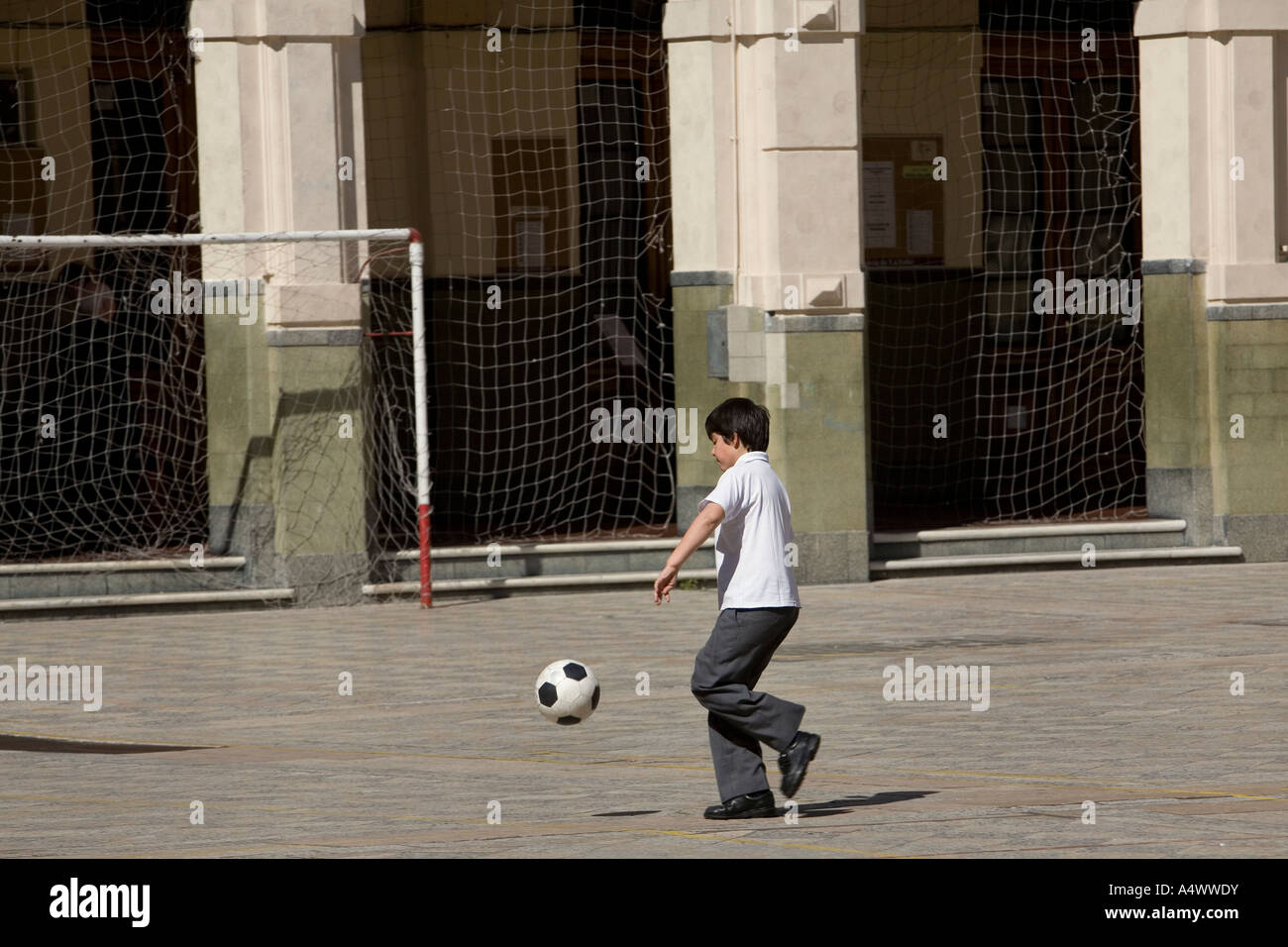 Young student playing soccer in courtyard Stock Photo - Alamy