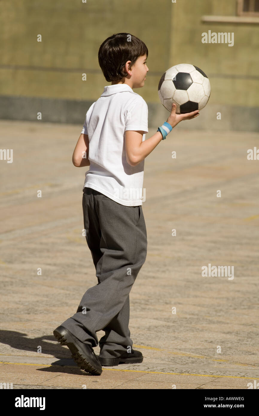Young student carrying soccer ball in courtyard Stock Photo - Alamy