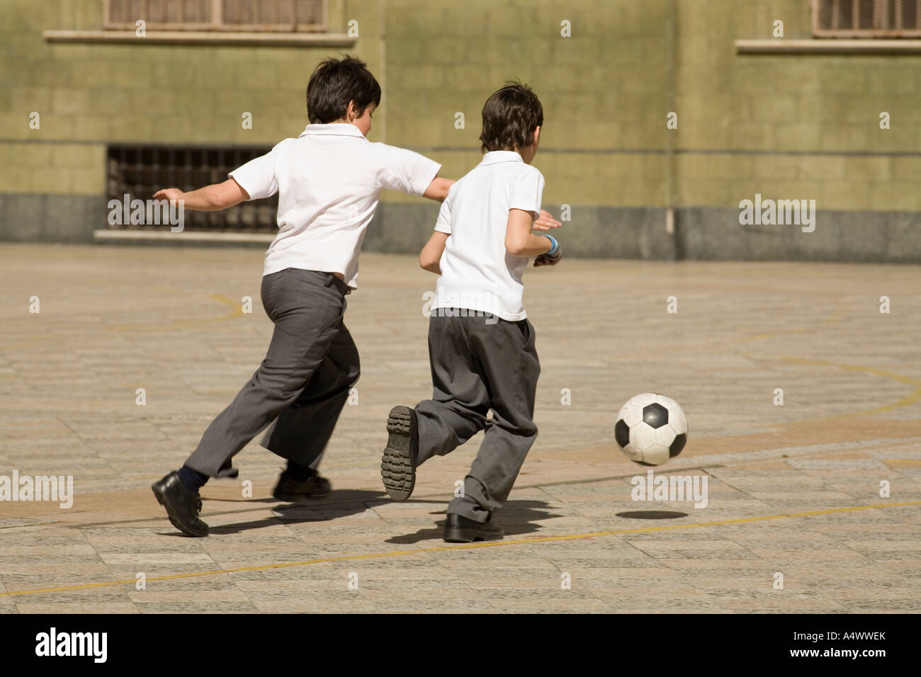 Young students playing soccer in courtyard Stock Photo - Alamy