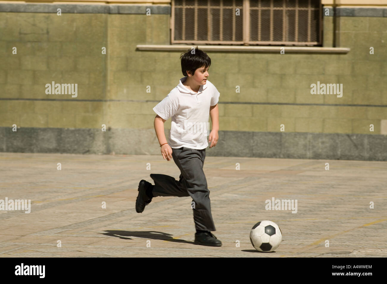 Young student playing soccer in courtyard Stock Photo - Alamy