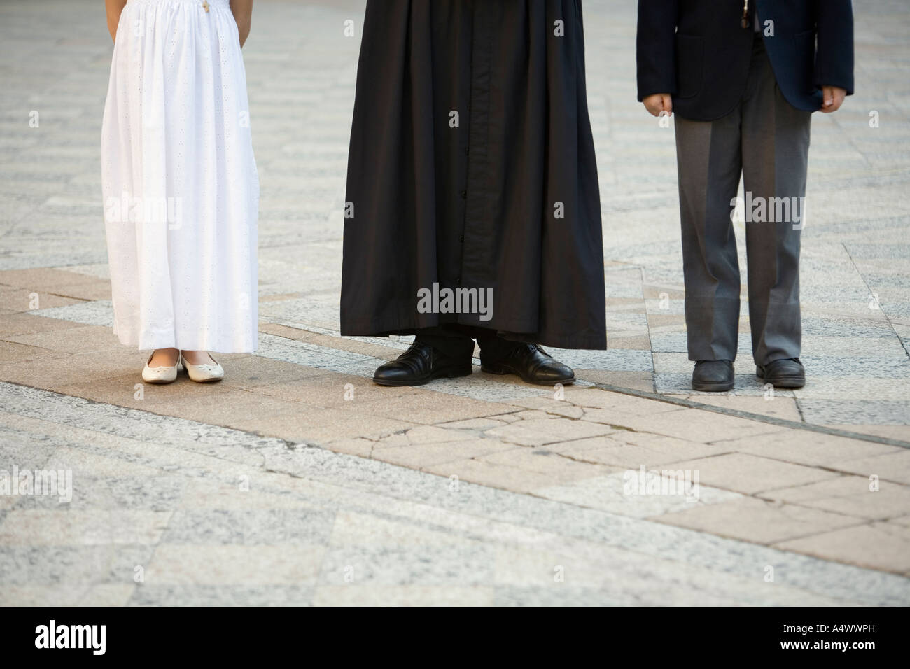 Robed priest standing with formally dressed children Stock Photo - Alamy