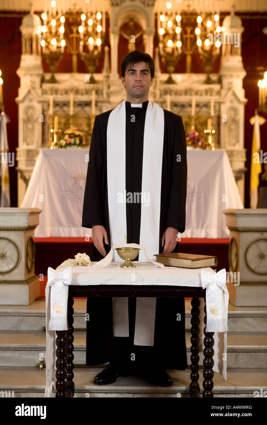 Robed priest standing at the altar of a church Stock Photo - Alamy