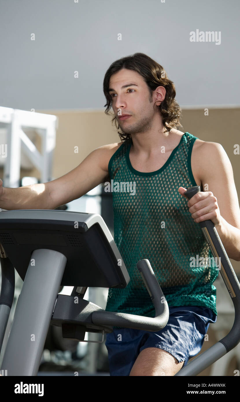 Man using the elliptical machine at a gym Stock Photo - Alamy