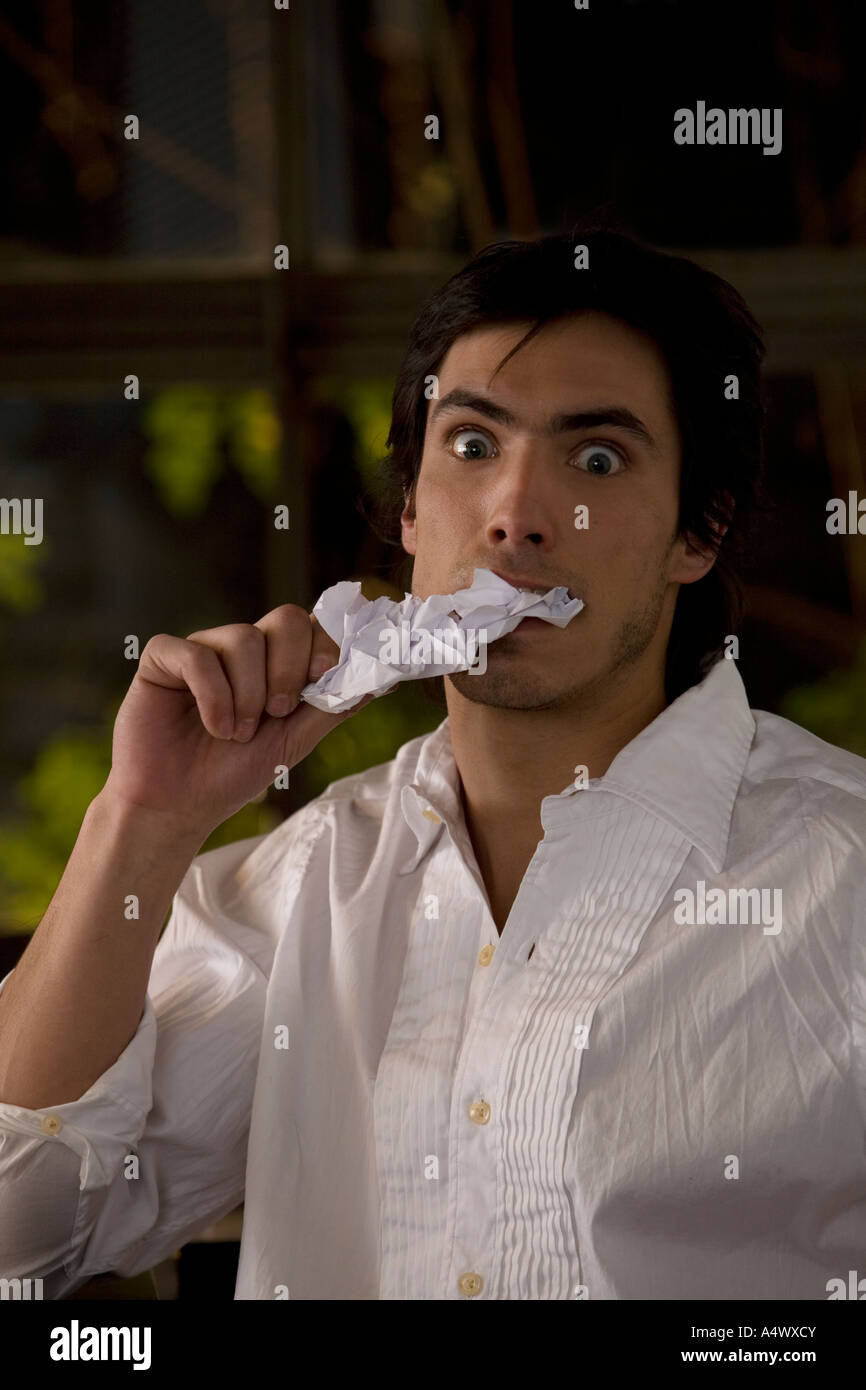 Man biting crumpled paper Stock Photo - Alamy