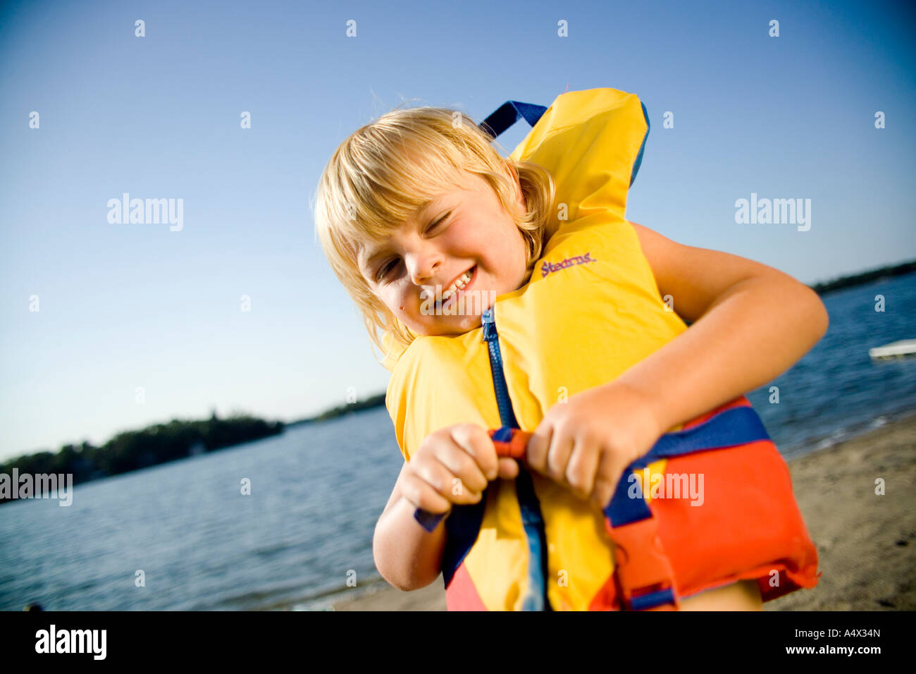 Boy putting on a life vest Stock Photo - Alamy