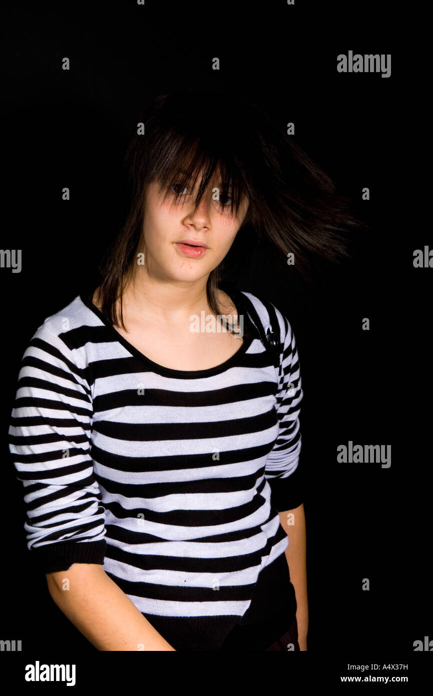 Young girl with fringe over her eyes looks confidently at the camera ...
