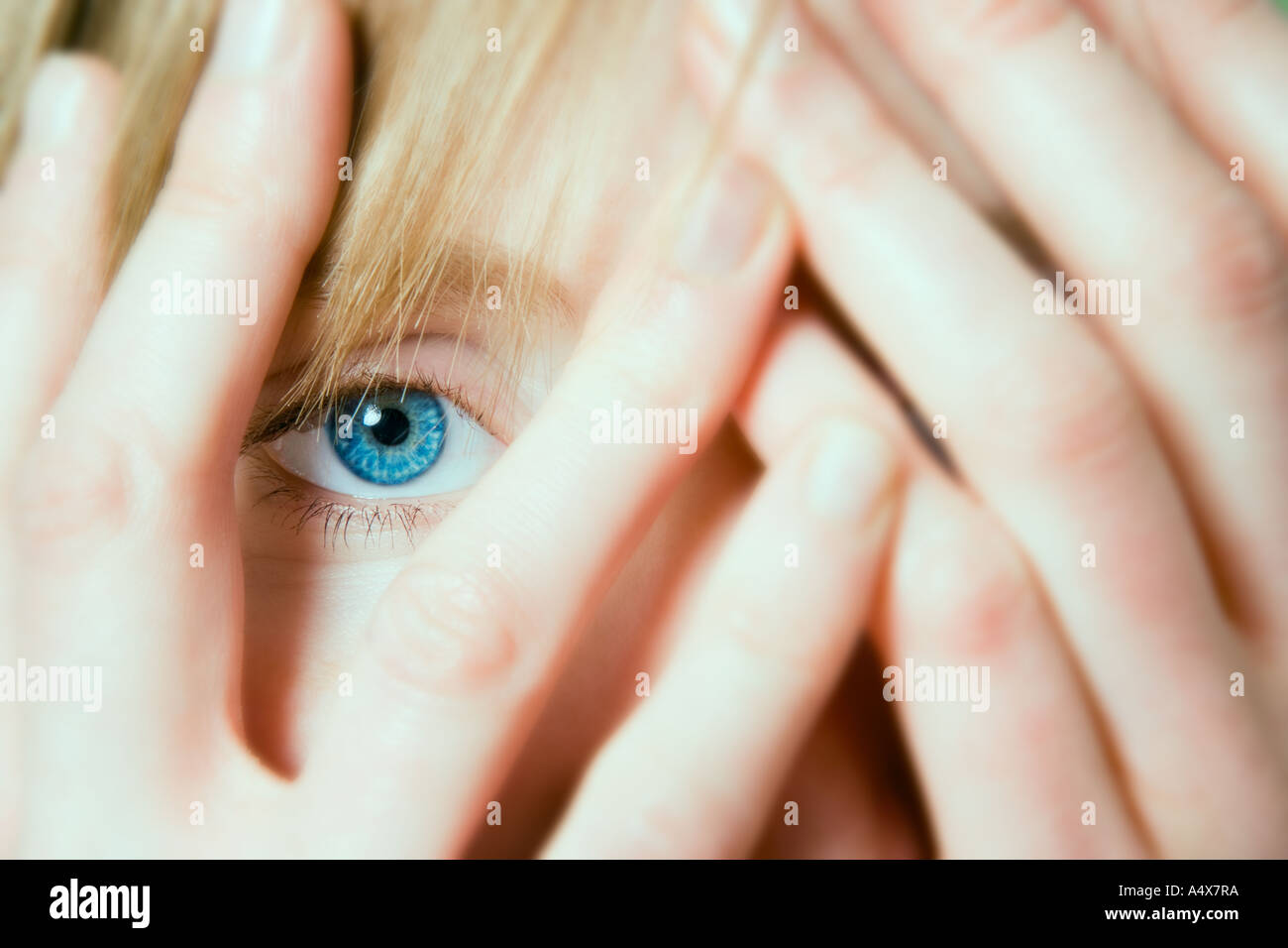 Young woman peeking through hands over face, close-up Stock Photo - Alamy
