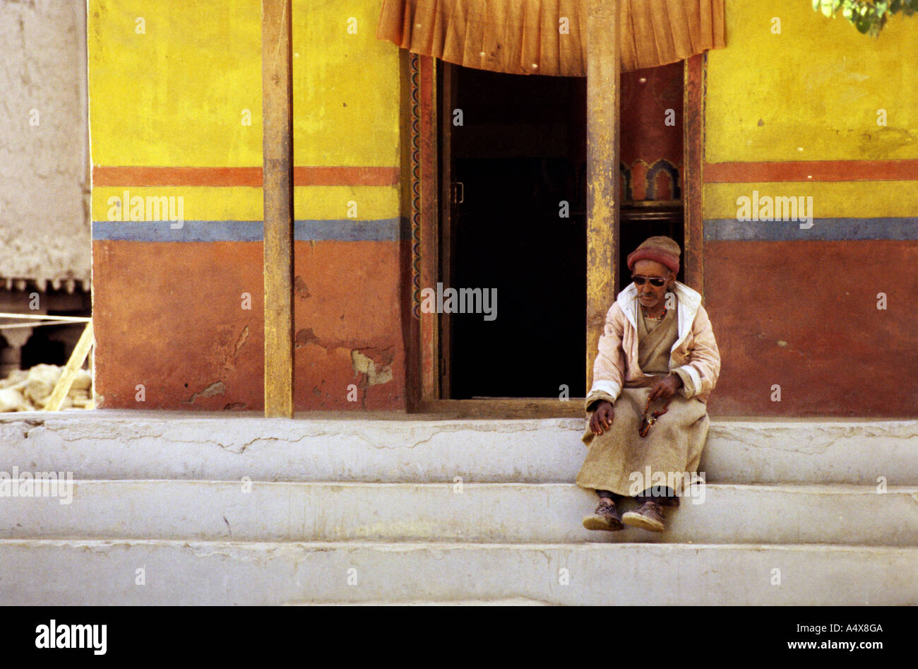 Old woman sitting at the gate of a house Stock Photo - Alamy