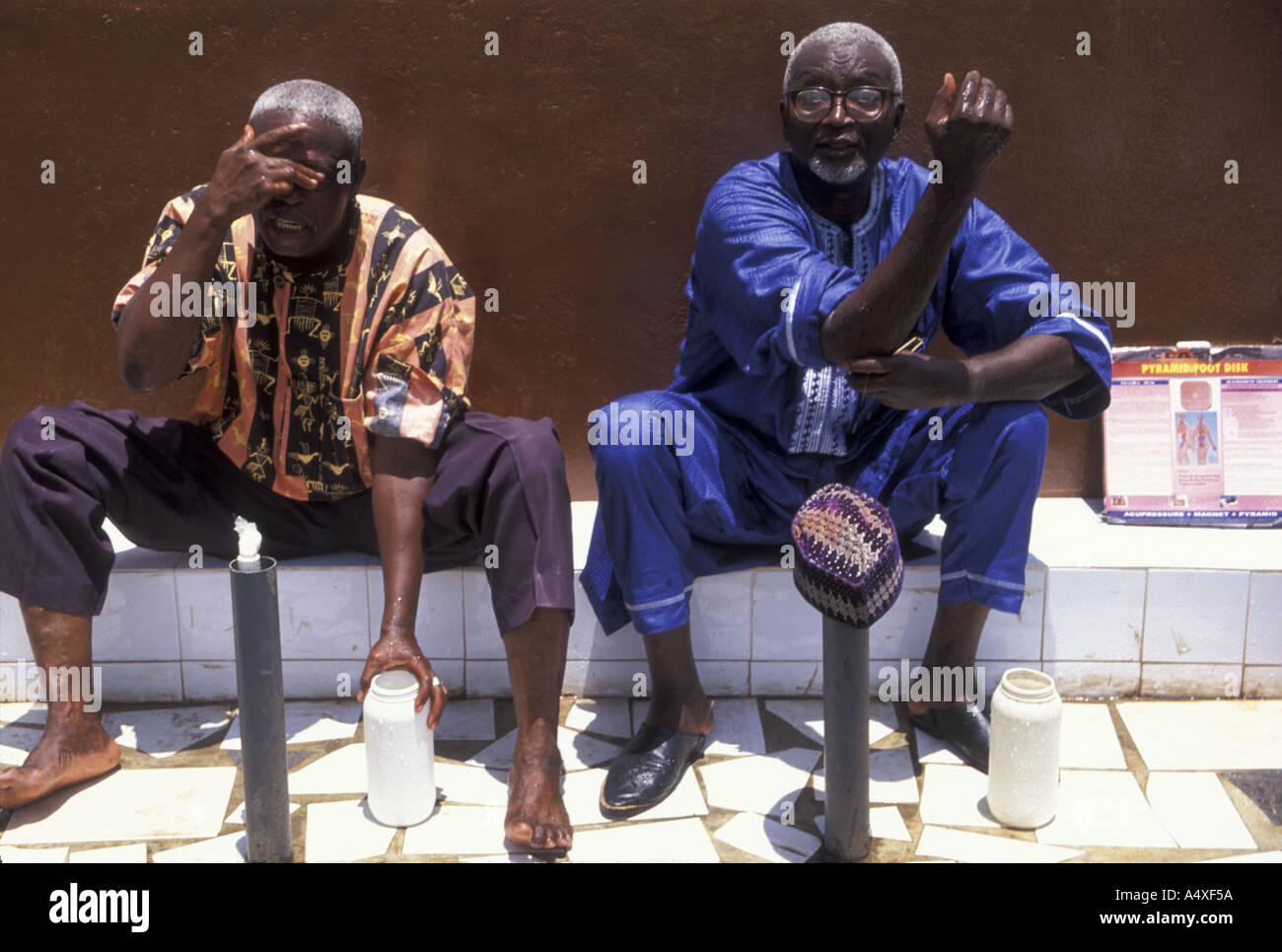 Two African Muslim men perform wudu or ablutions outside a mosque in ...
