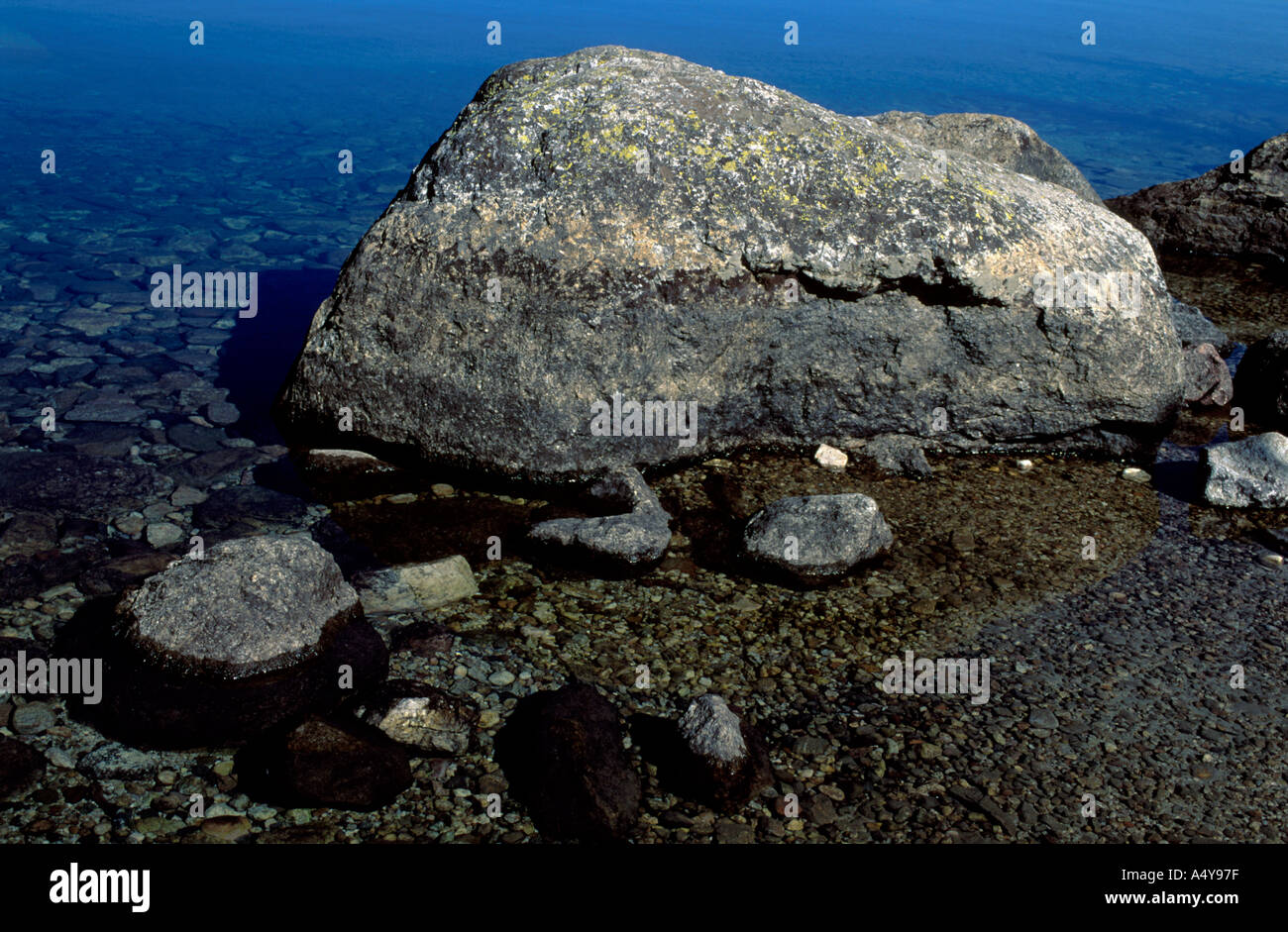 Rocks at edge of lake with reflection of blue sky jenny lake grand ...