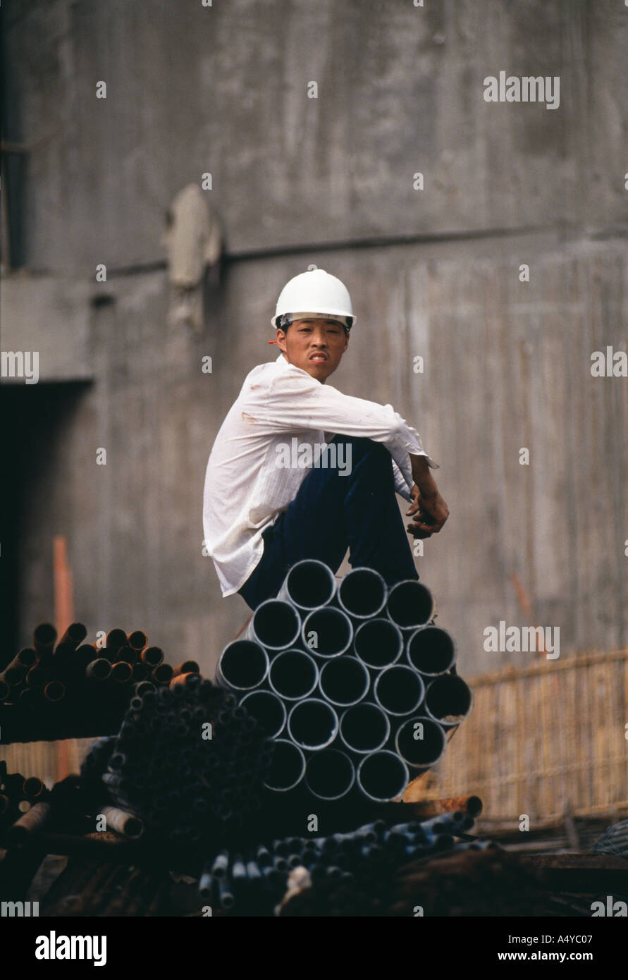 Chinese construction worker sitting on pile of pipes Bejing China Stock ...