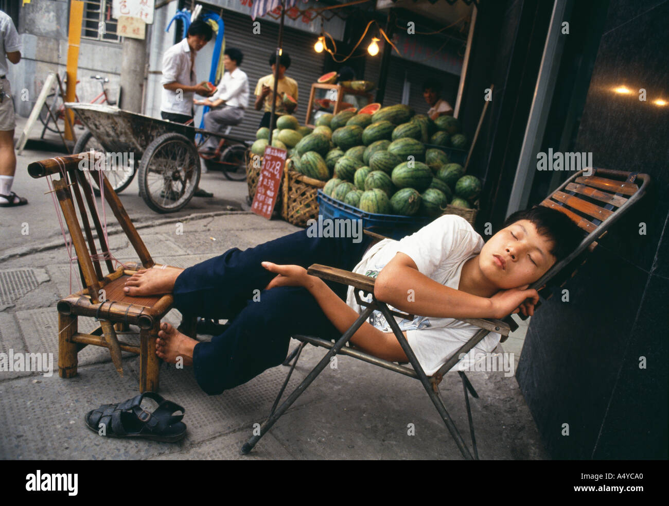 Chinese boy sleeps on the street beside his melon stall shanghai china ...