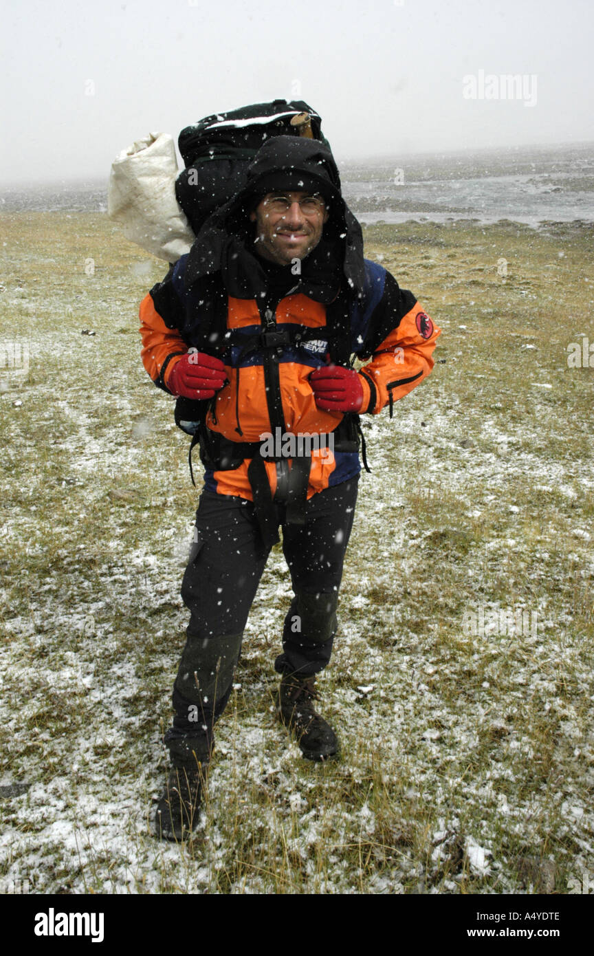 Trekking mountaineer carrying his backpack in snowfall in the steppe ...