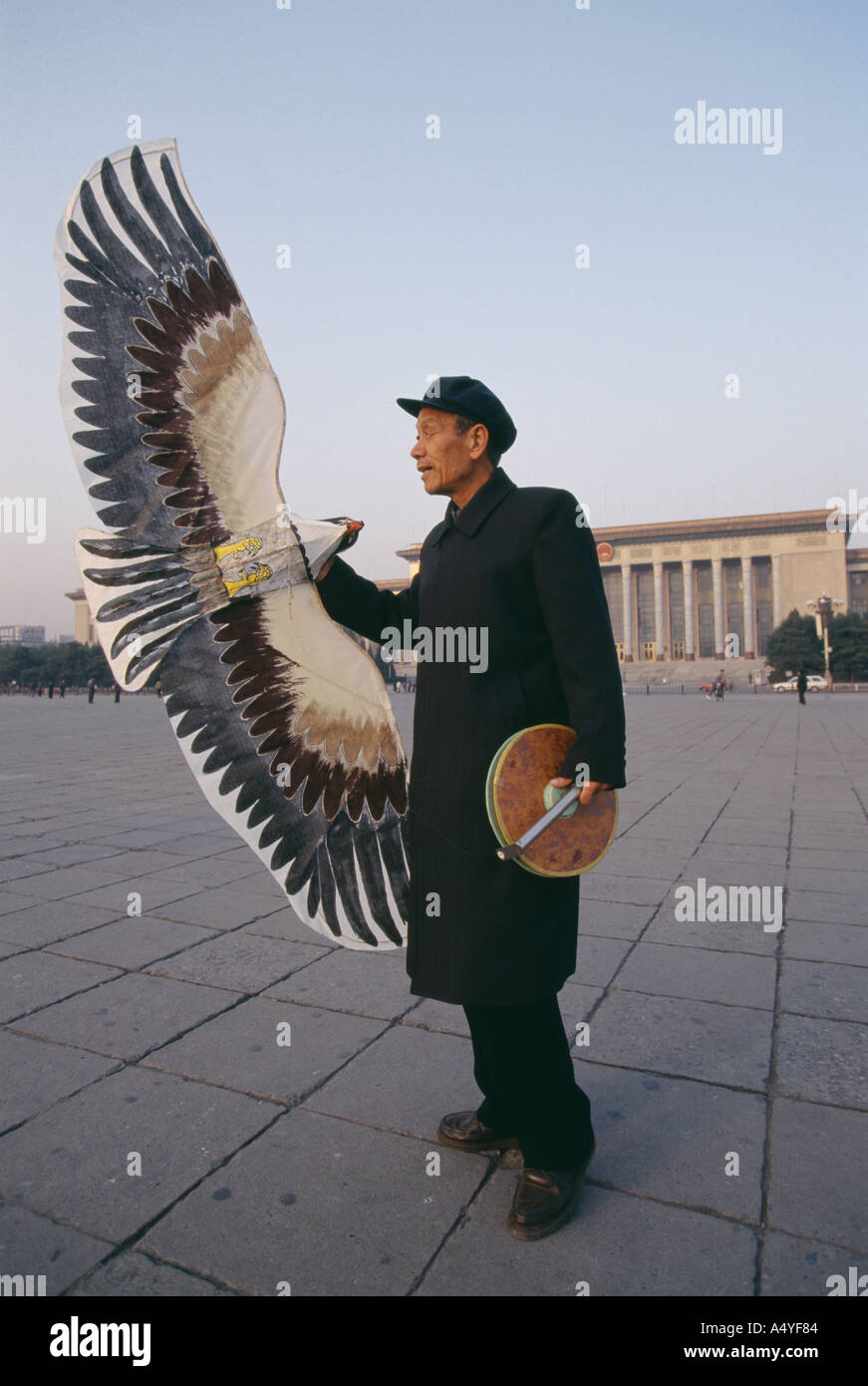 senior Chinese Man preparesto fly bird shaped kite Tiananmen Square ...
