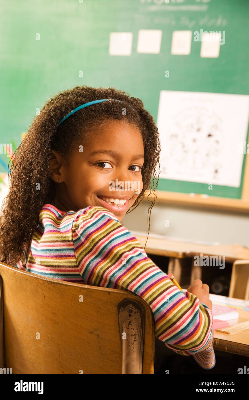 Girl smiling over shoulder in classroom Stock Photo - Alamy