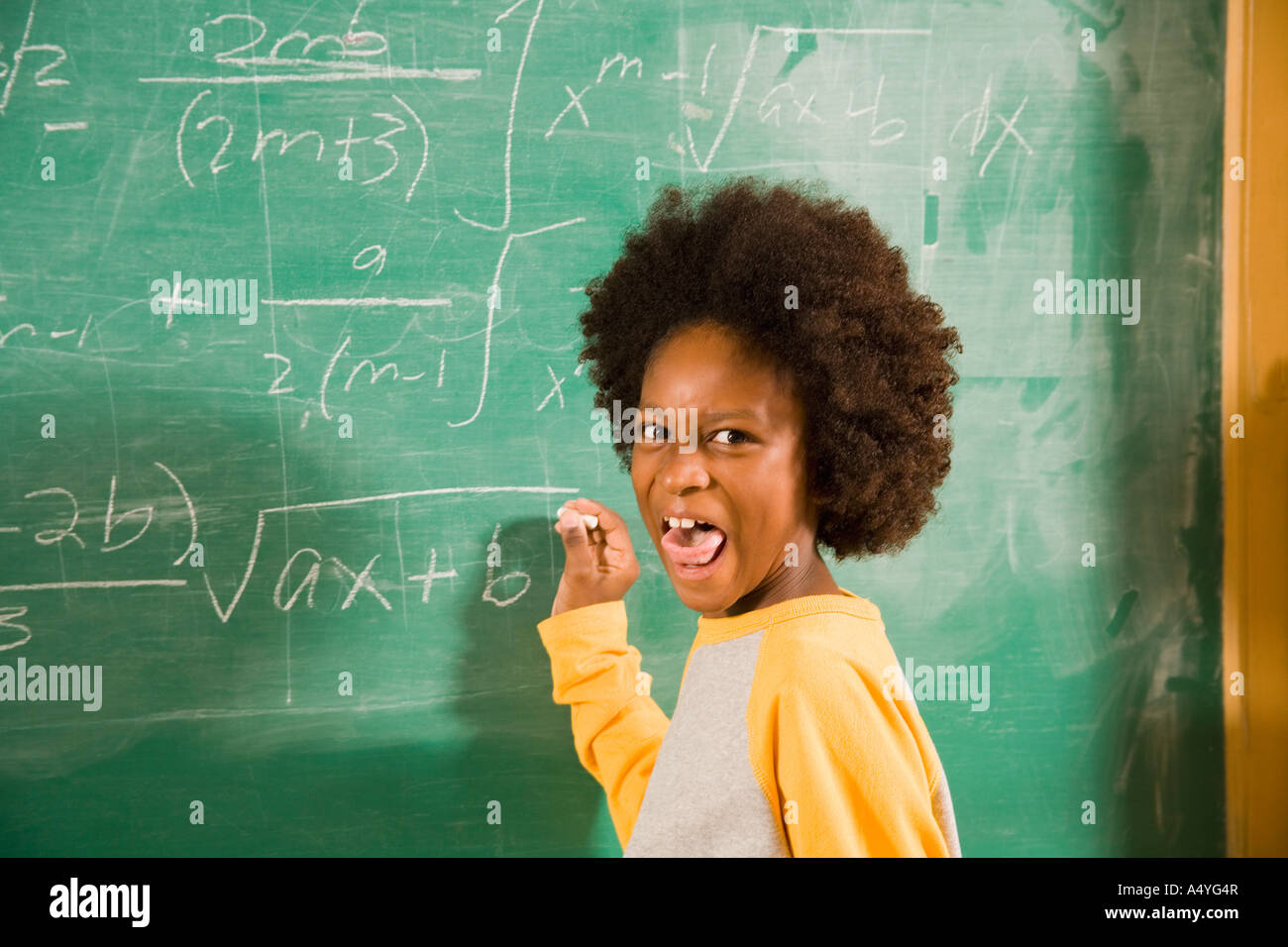 Boy sticking out tongue and writing on blackboard Stock Photo - Alamy
