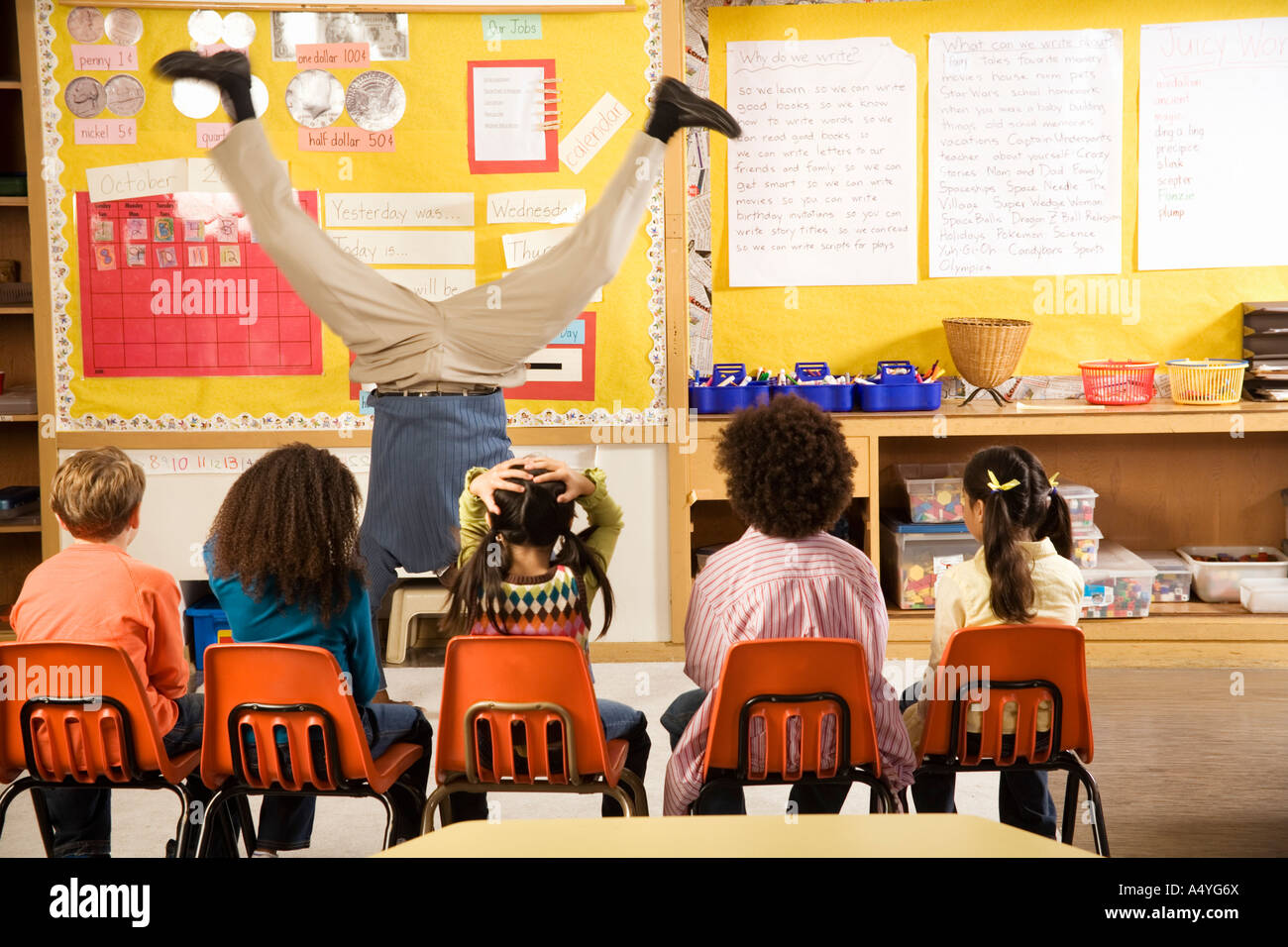 Male teacher doing handstand in classroom Stock Photo - Alamy