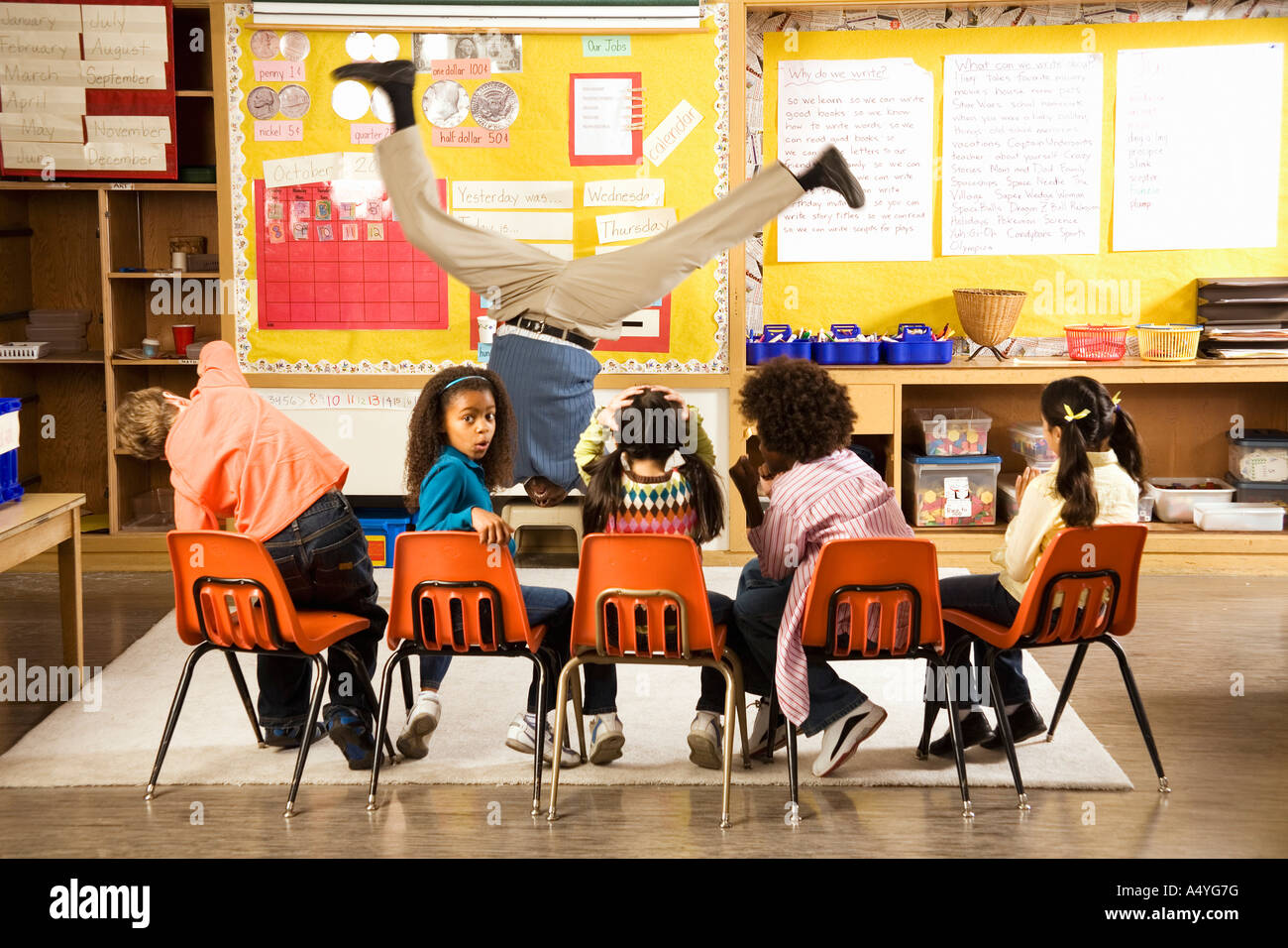 Male teacher doing handstand in classroom Stock Photo - Alamy