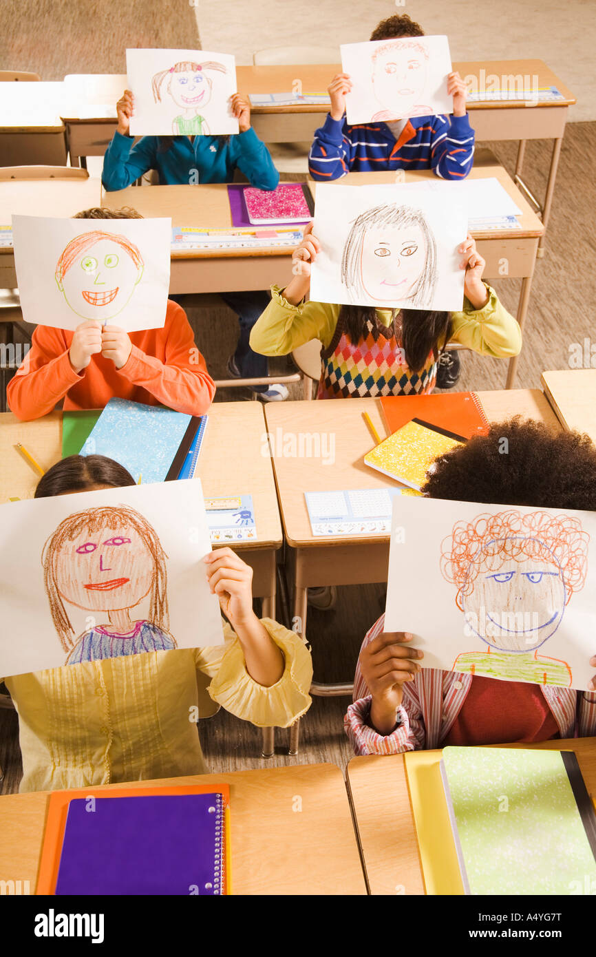 Students holding drawings over faces in classroom Stock Photo - Alamy