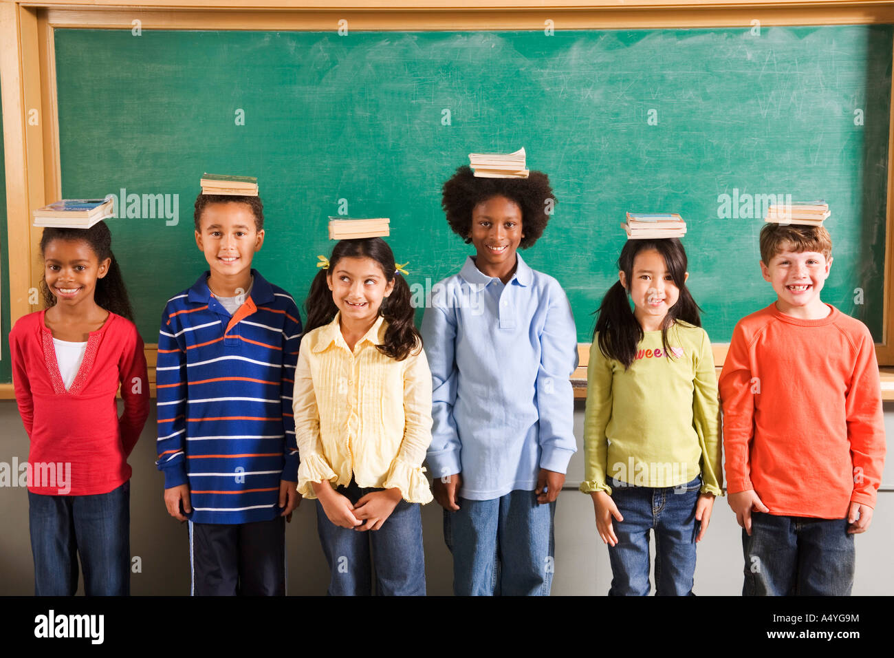 Row of students with books on their heads in classroom Stock Photo - Alamy